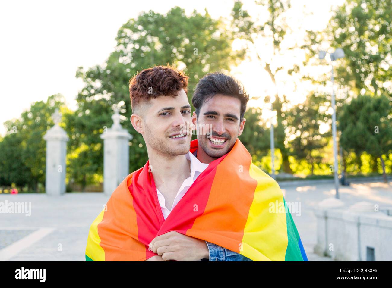 Couple of homosexual men embracing and covered with a LGBT Pride flag ...