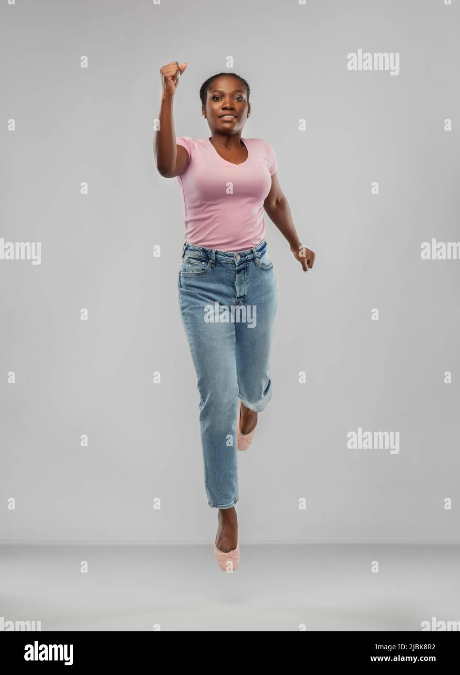 happy african american woman jumping over grey Stock Photo - Alamy