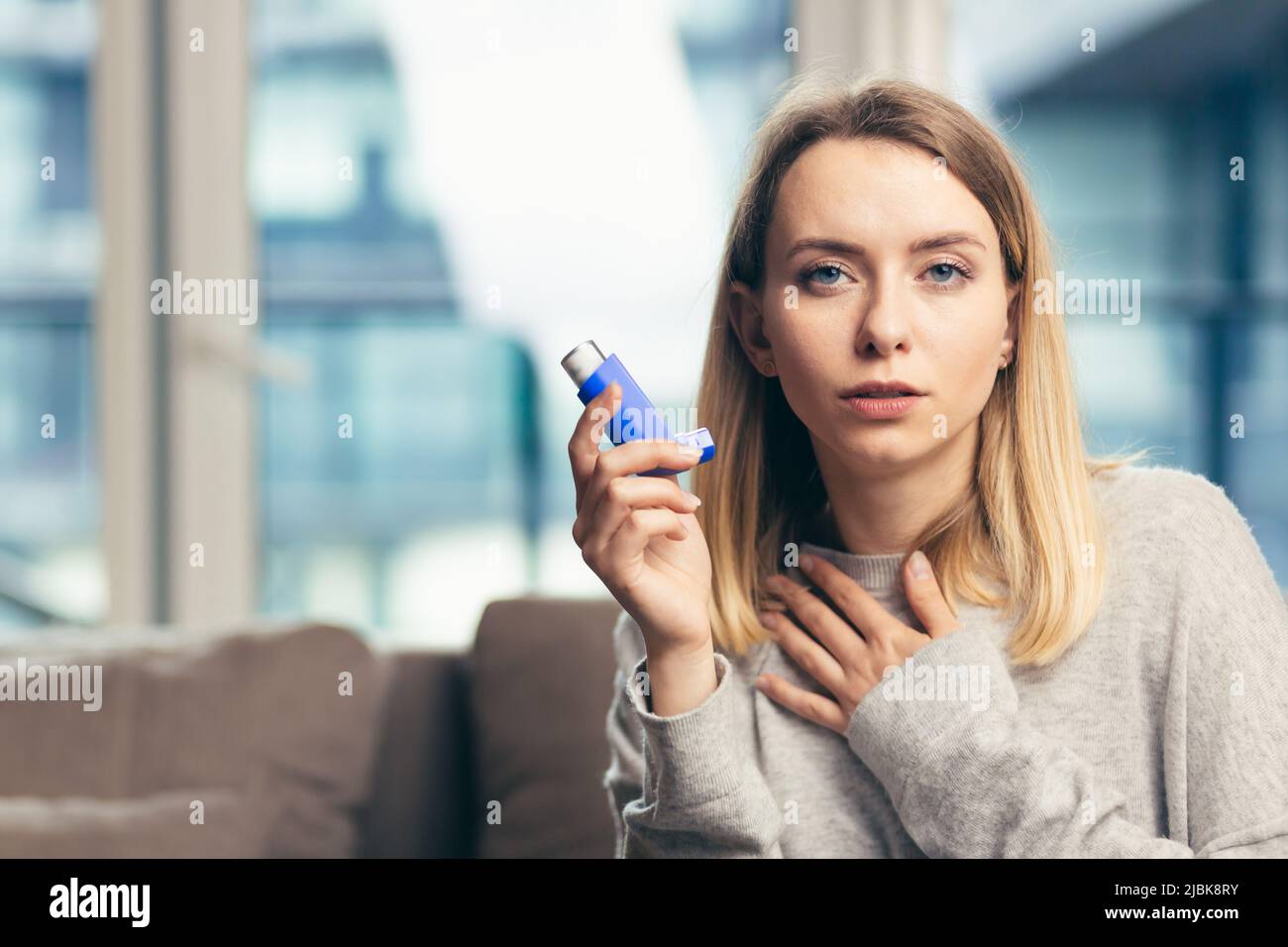 Young woman uses inhaler for asthma, cough, sick at home, holding ...
