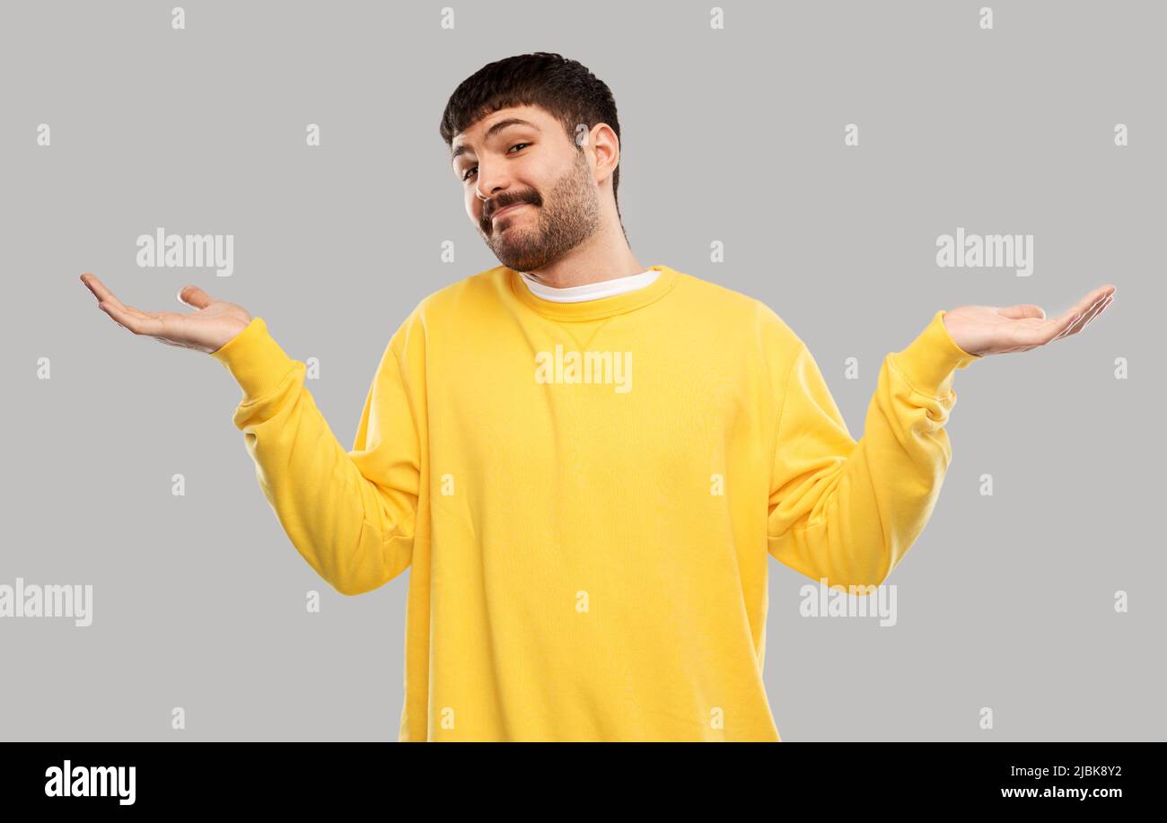 confused man in yellow sweatshirt shrugging Stock Photo - Alamy