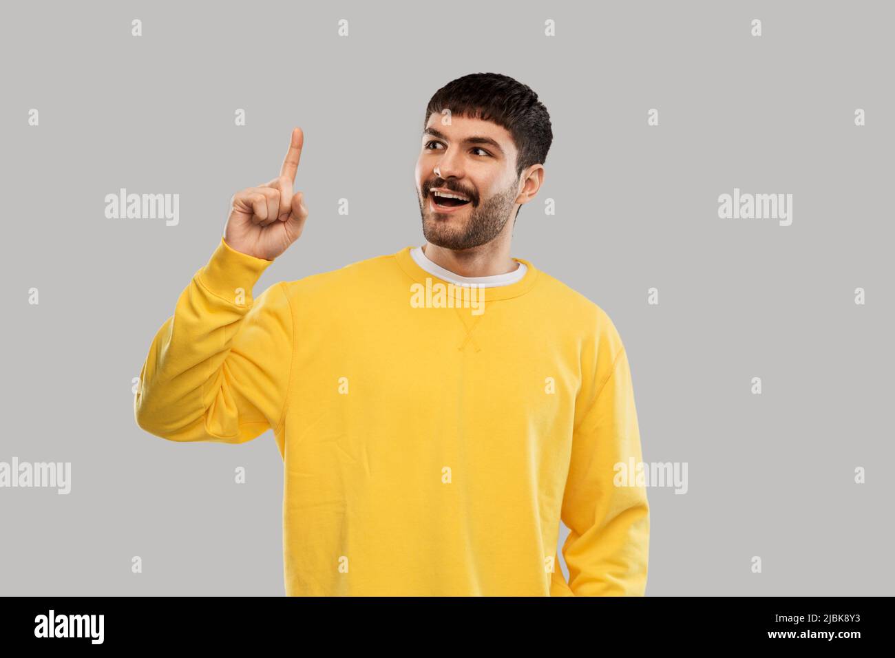 young man showing one finger in yellow sweatshirt Stock Photo - Alamy