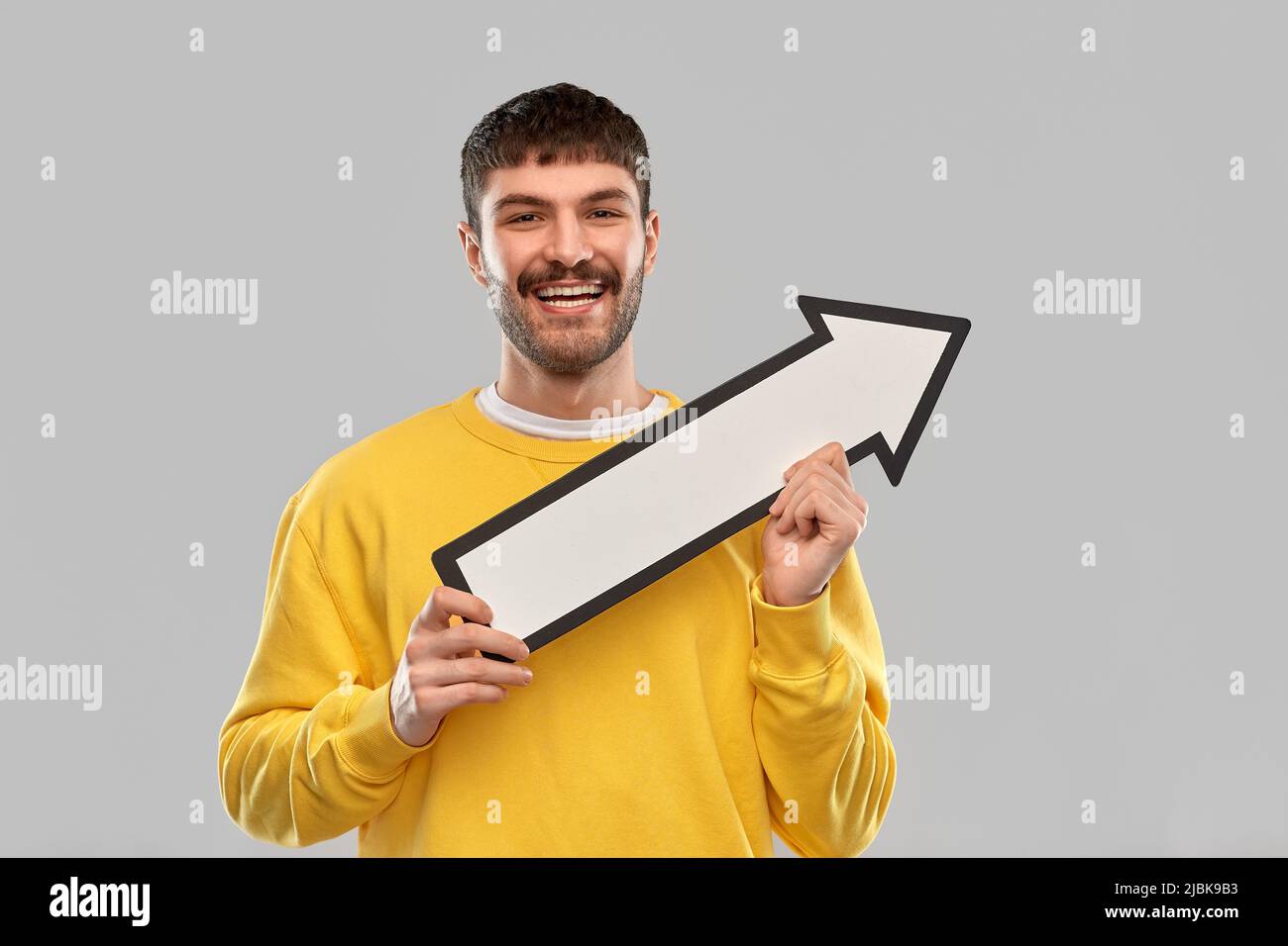 smiling man holding big arrow pointing to right Stock Photo - Alamy