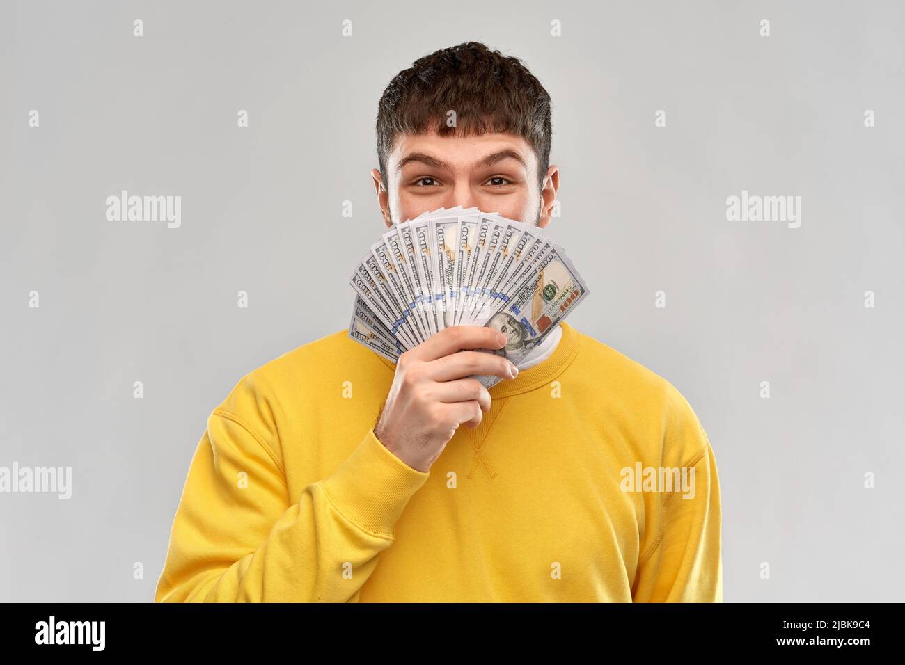 happy young man in yellow sweatshirt with money Stock Photo - Alamy
