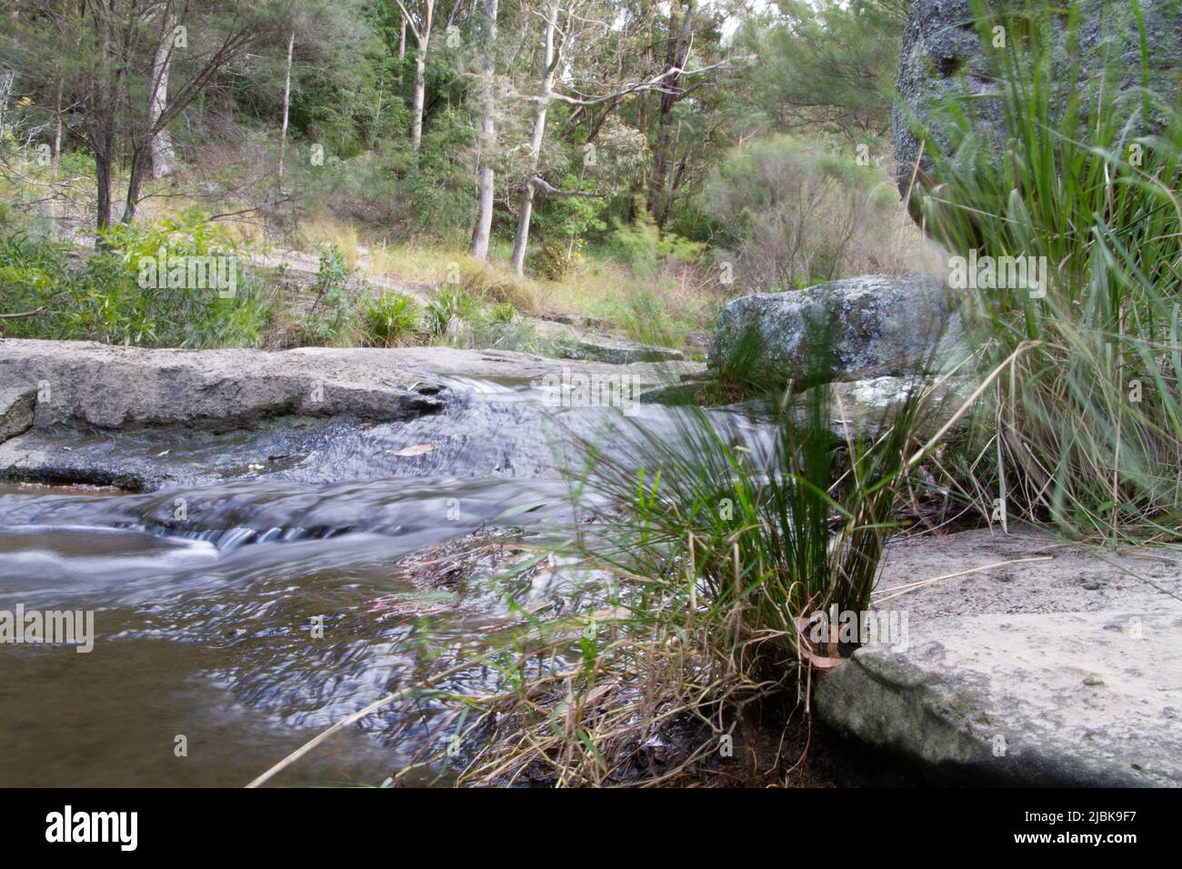 Waterfall behind tuff of grass Stock Photo - Alamy