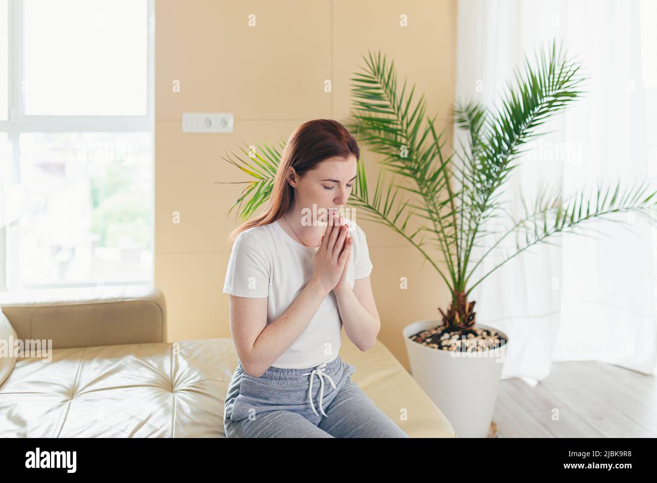 Closeup portrait of a young woman praying sincerely with folded arms at ...