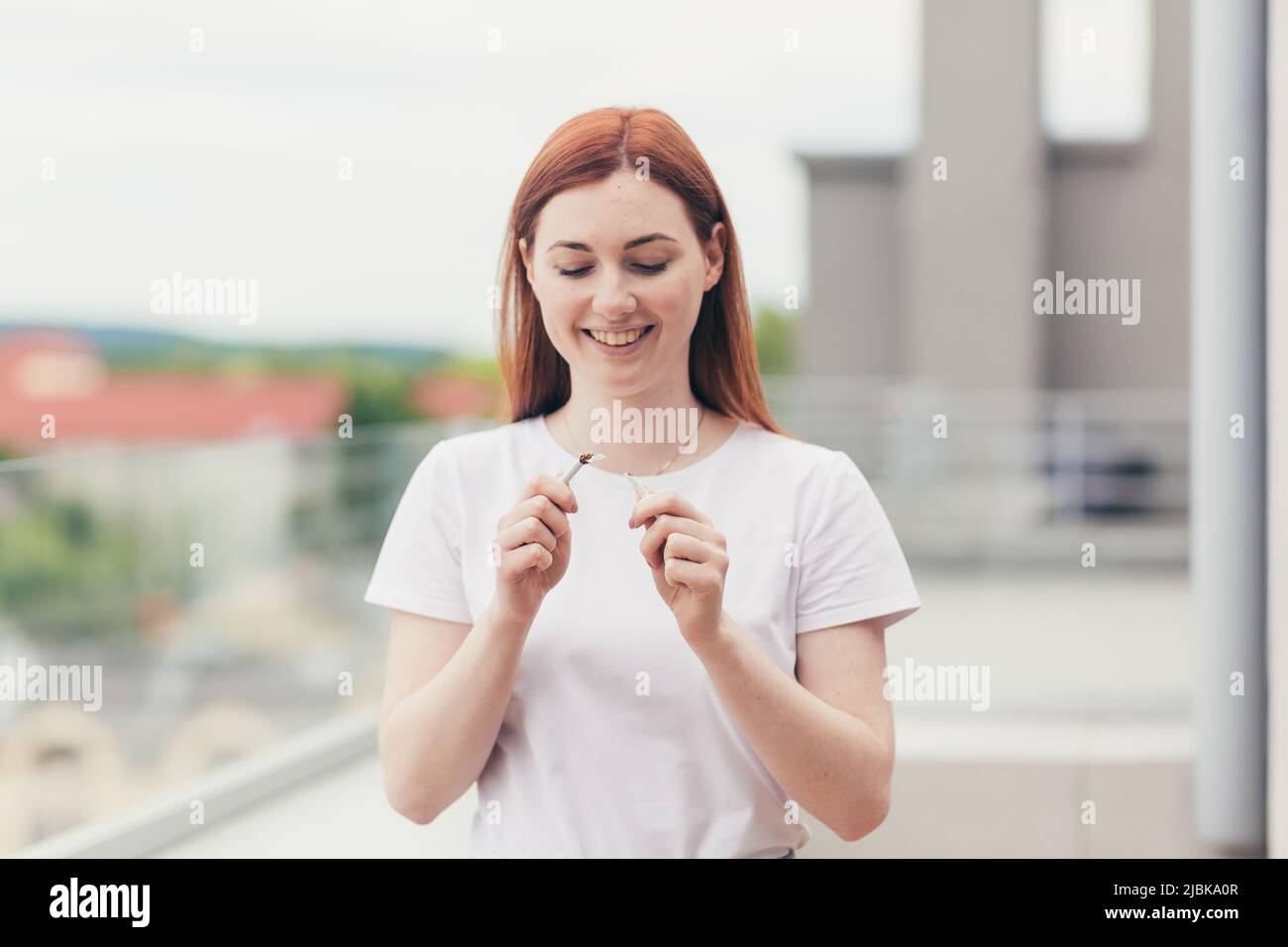 A young woman breaks a cigarette as a sign that she has quit smoking ...