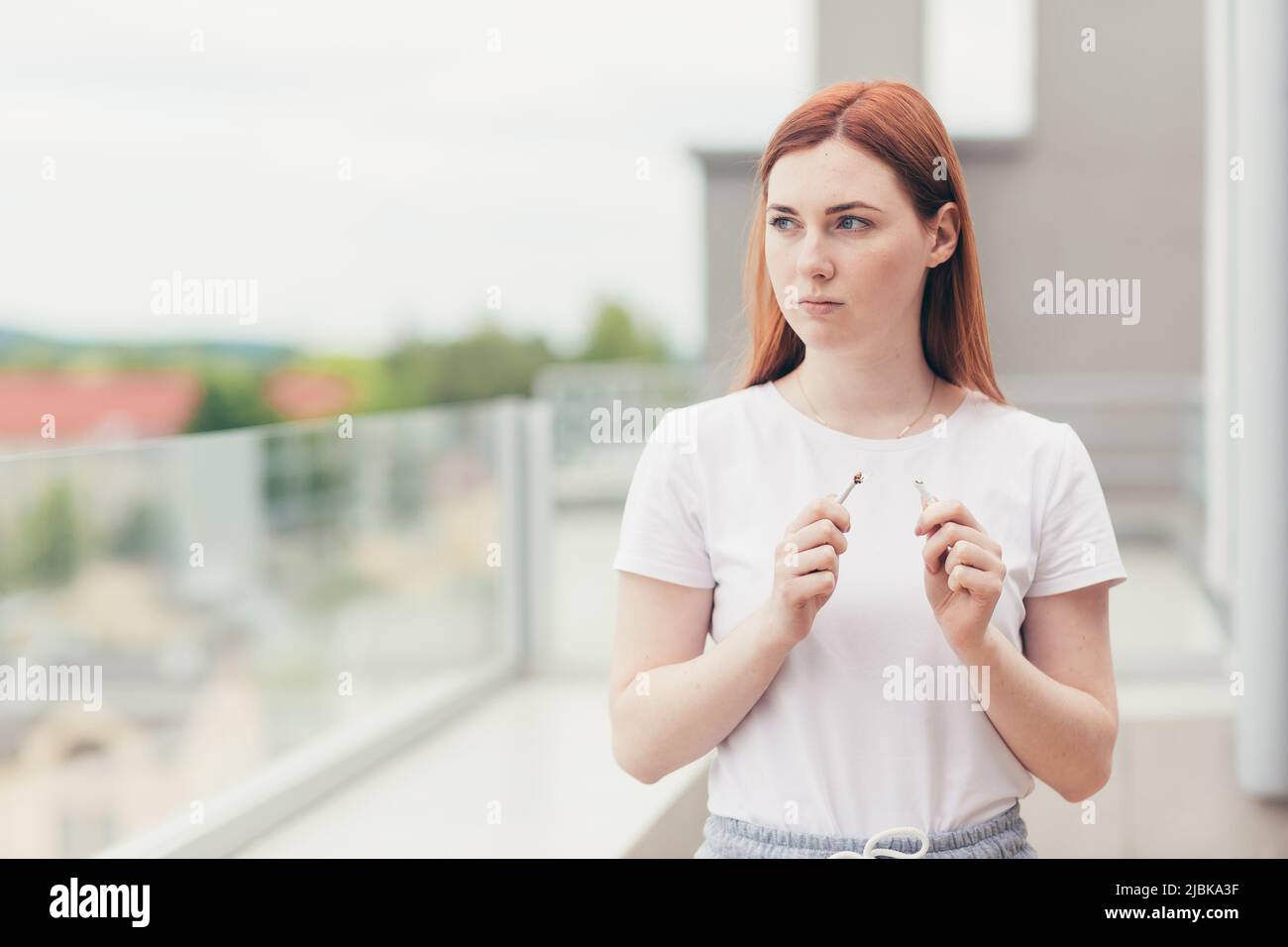 A young woman breaks a cigarette as a sign that she has quit smoking ...