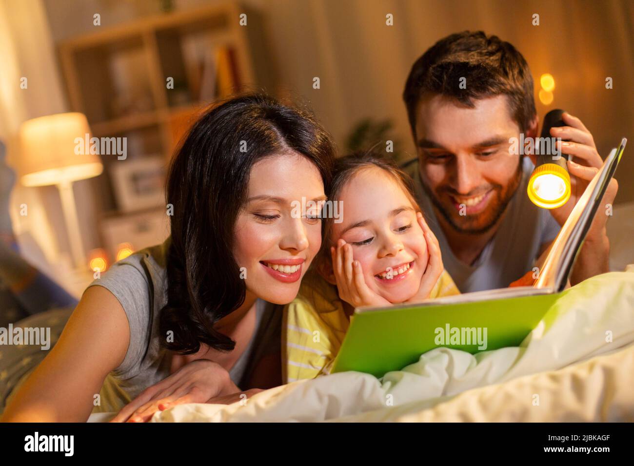 happy family reading book in bed at night at home Stock Photo - Alamy
