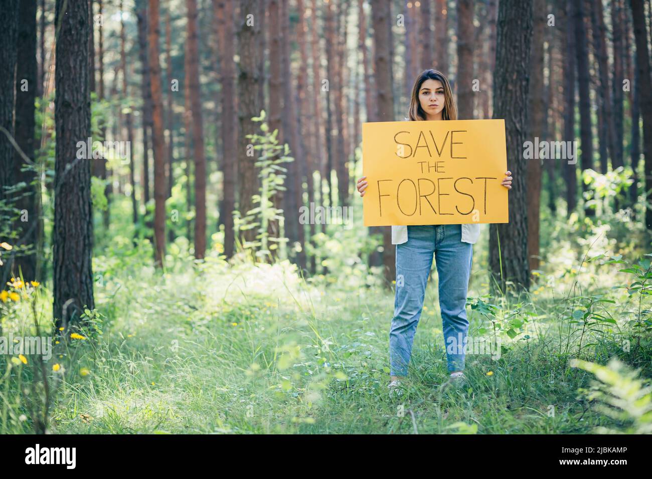 young beautiful woman volunteer activist in the forest with a poster save the forest Stock Photo ...