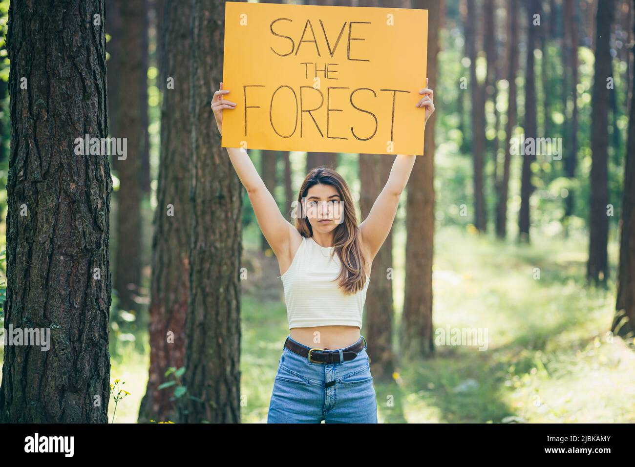 young beautiful woman volunteer activist in the forest with a poster ...