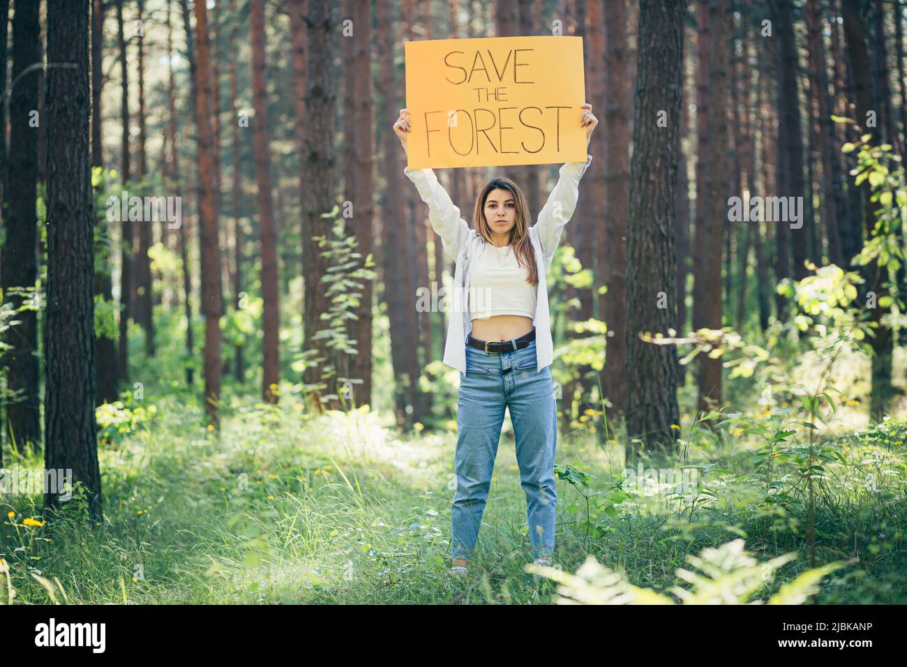 young beautiful woman volunteer activist in the forest with a poster ...