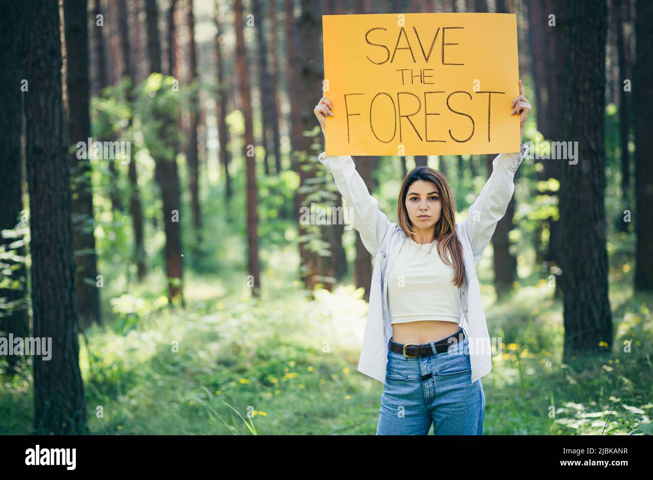 young beautiful woman volunteer activist in the forest with a poster ...