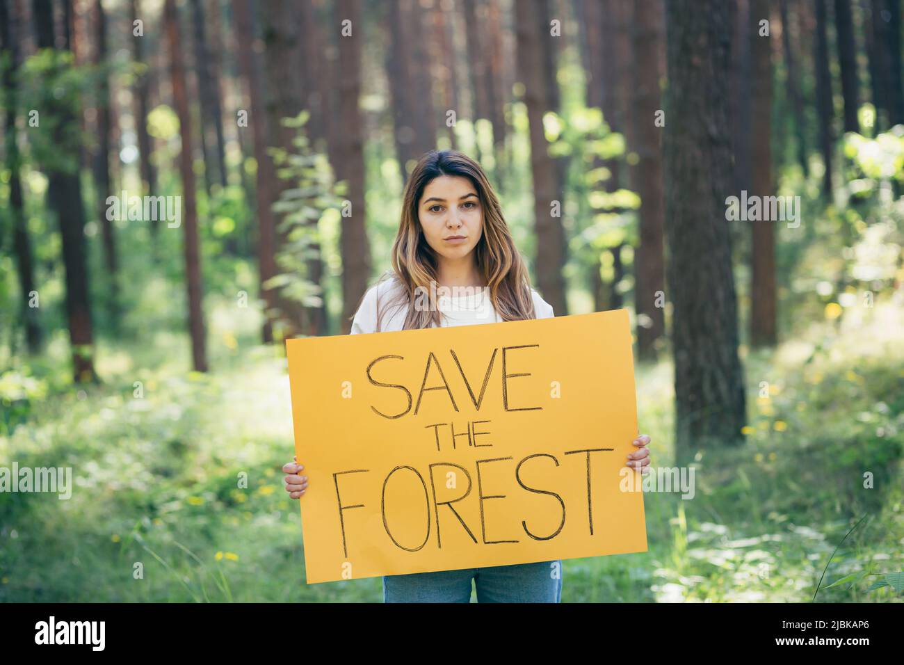 young beautiful woman volunteer activist in the forest with a poster ...