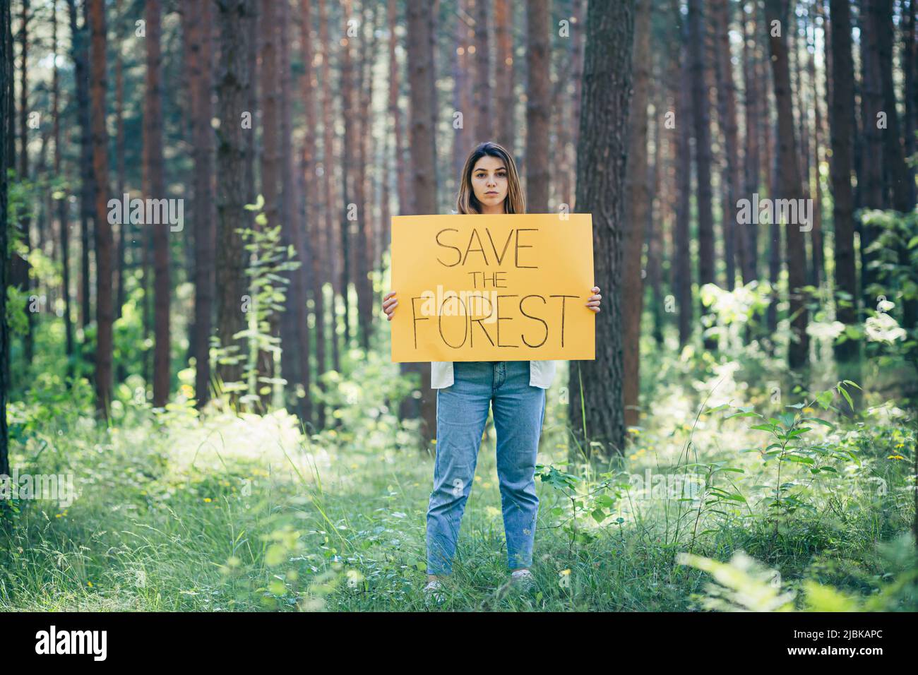 young beautiful woman volunteer activist in the forest with a poster ...