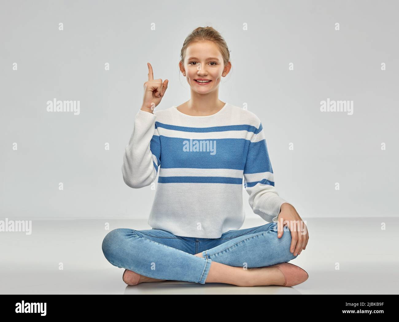 teenage girl pointing finger up sitting on floor Stock Photo - Alamy