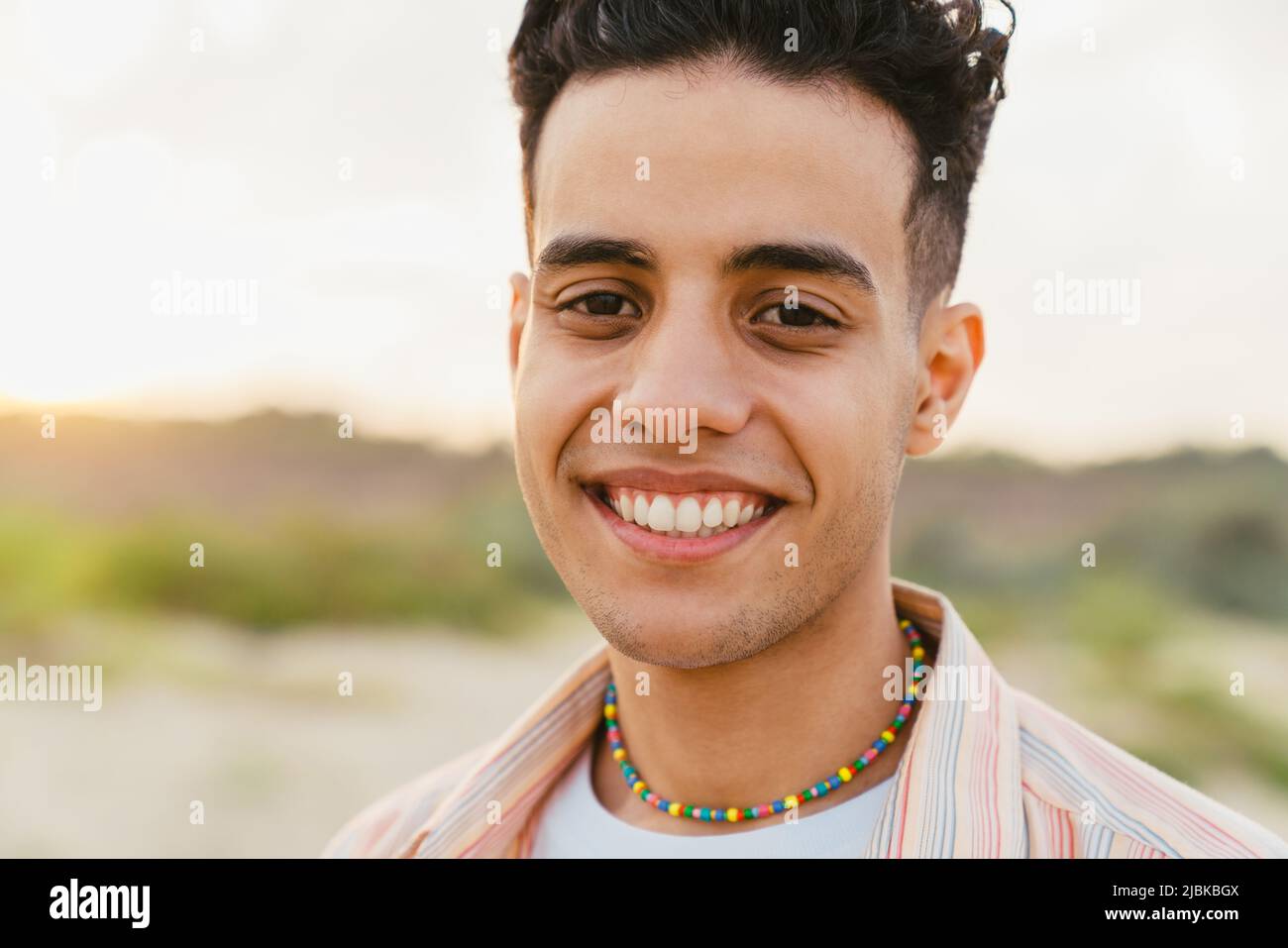 Young middle eastern man smiling during walking on summer beach Stock ...