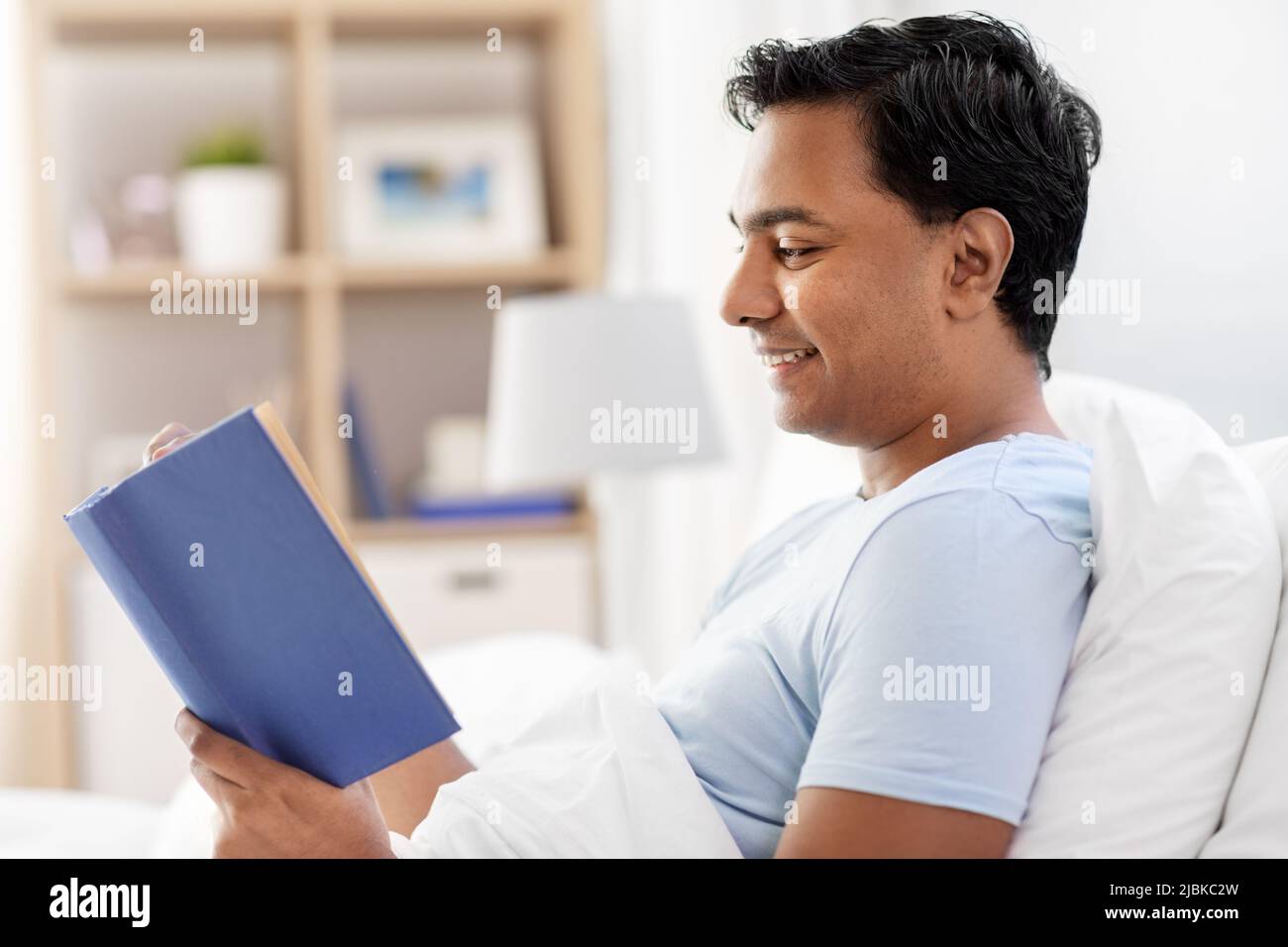 happy indian man reading book in bed at home Stock Photo - Alamy