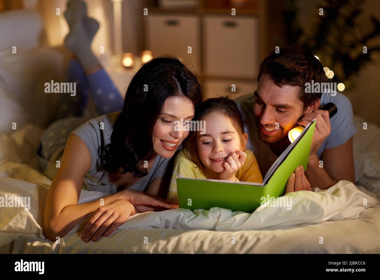 happy family reading book in bed at night at home Stock Photo - Alamy