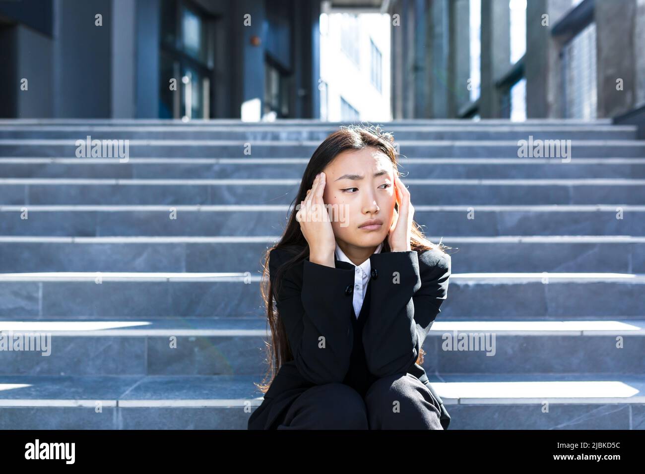 Asian woman with strong headdress sitting on stairs, sick and sad ...