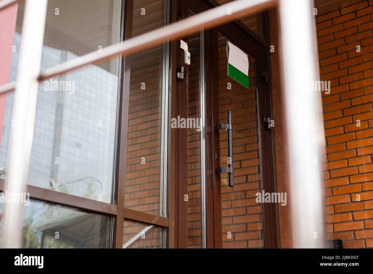 The front door of a office block, reflecting buildings in the glass ...