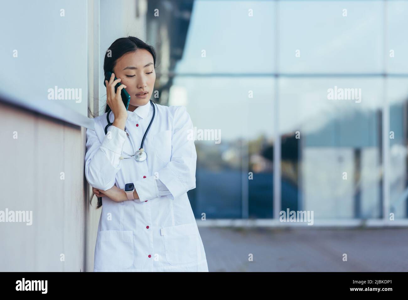 Sad and frustrated female doctor talking on the phone near the clinic ...