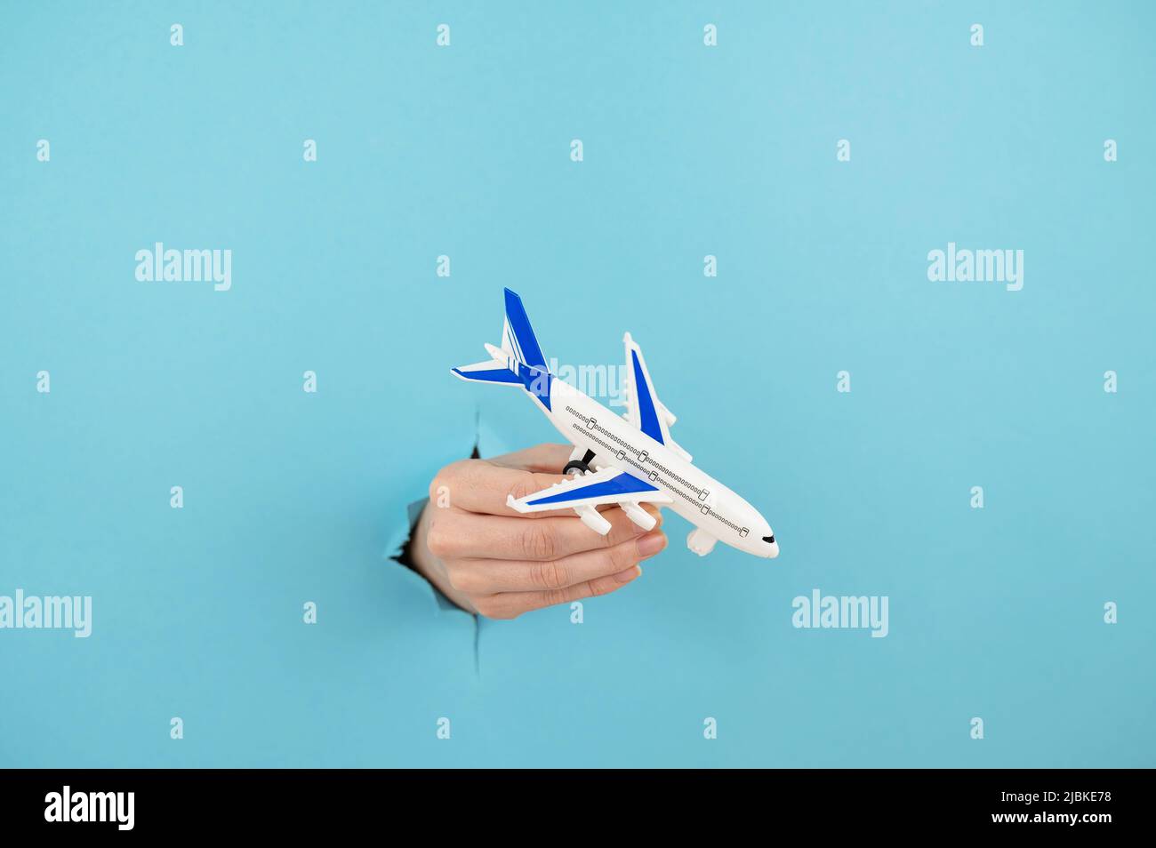 A female hand sticking out of a hole from a blue background holds a ...