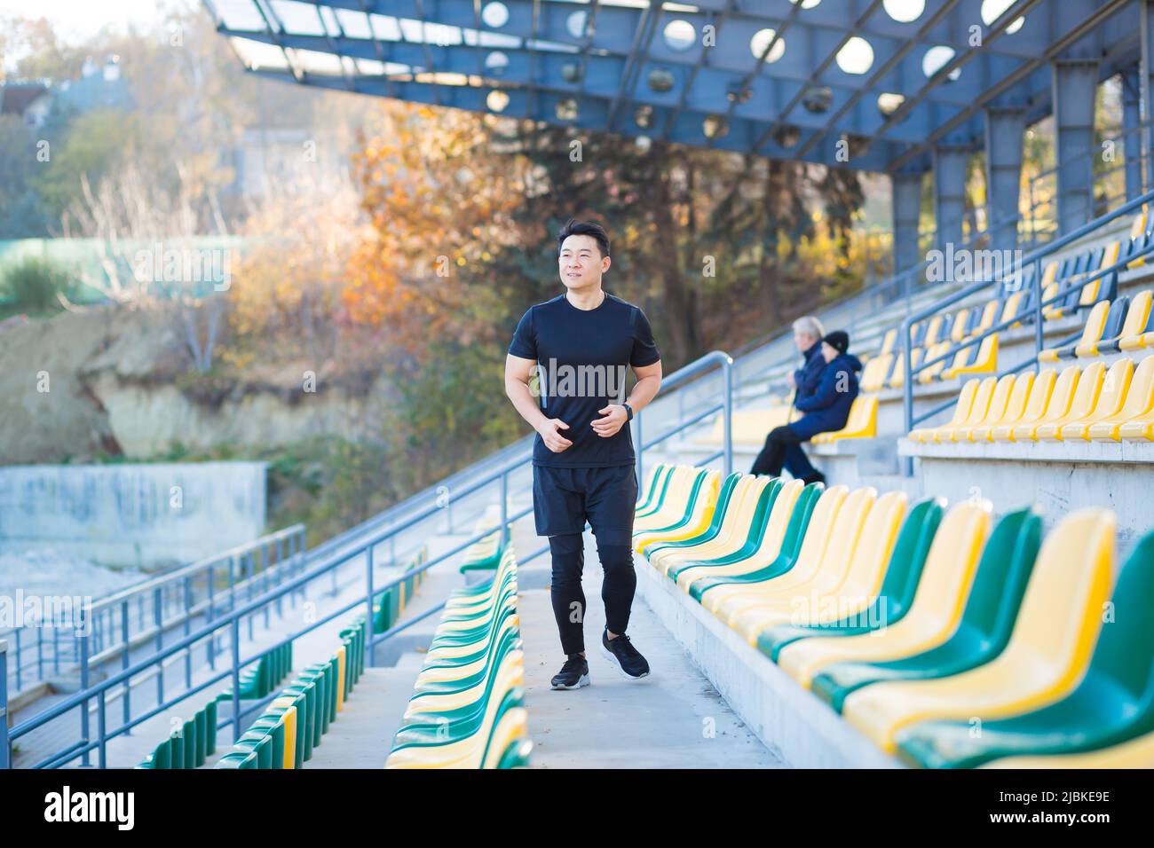 Asian male runner running around modern urban stadium up stairs Cardio ...