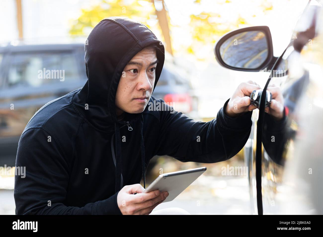 male bandit thief car thief asian uses a tablet to turn off the car ...