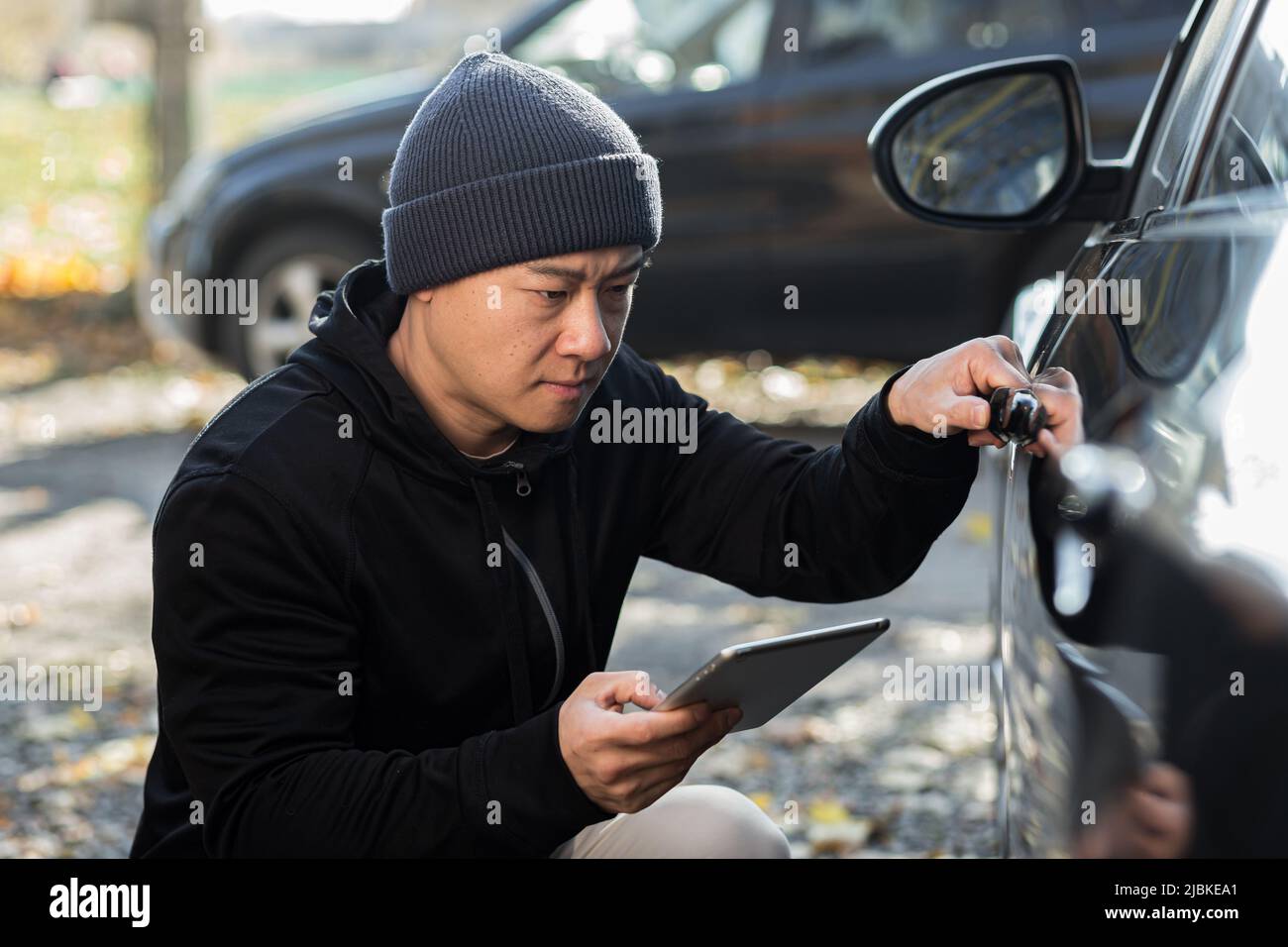 male bandit thief car thief asian uses a tablet to turn off the car ...