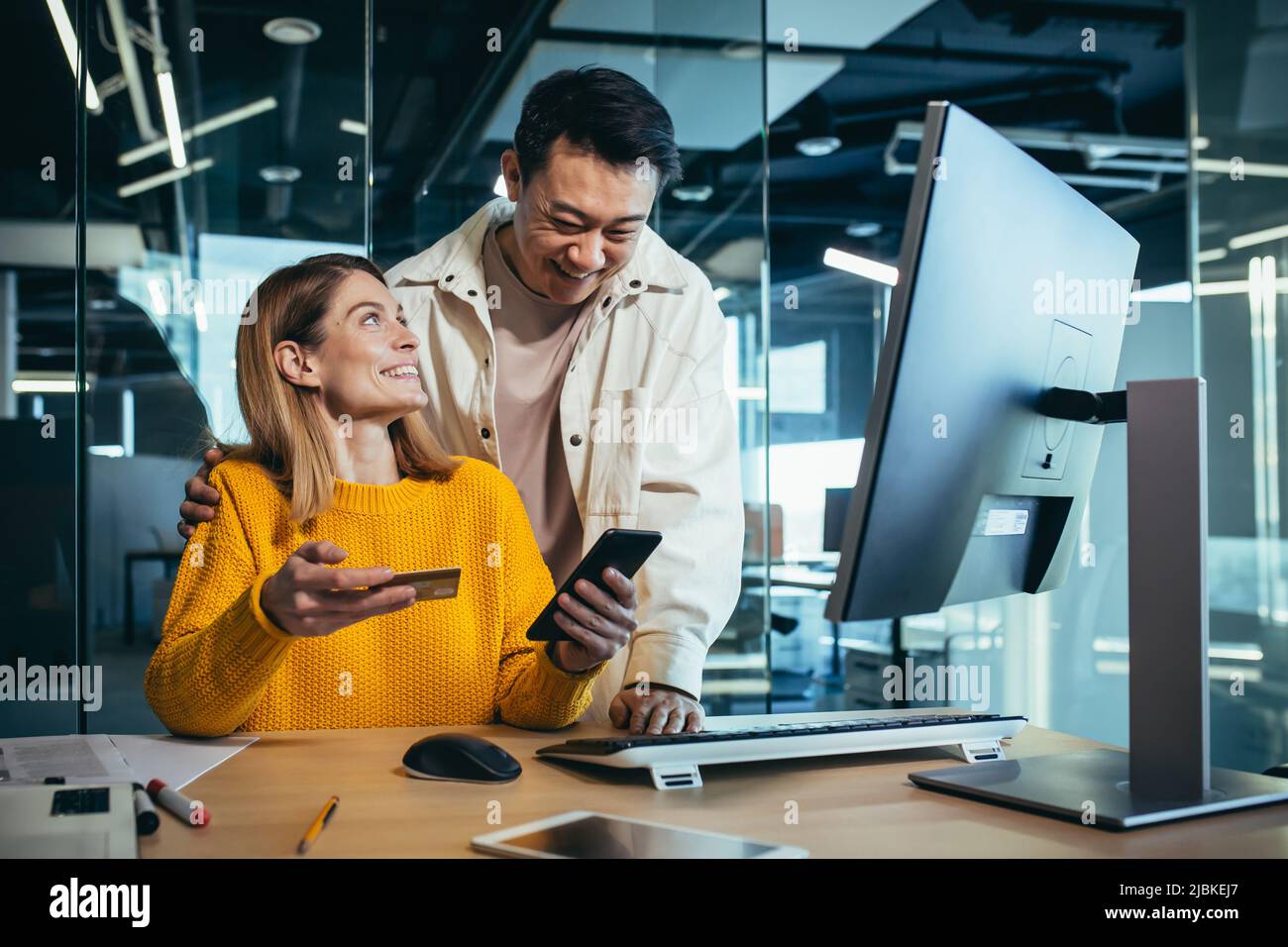Creative team of Asian man and woman shopping online, sitting at a ...