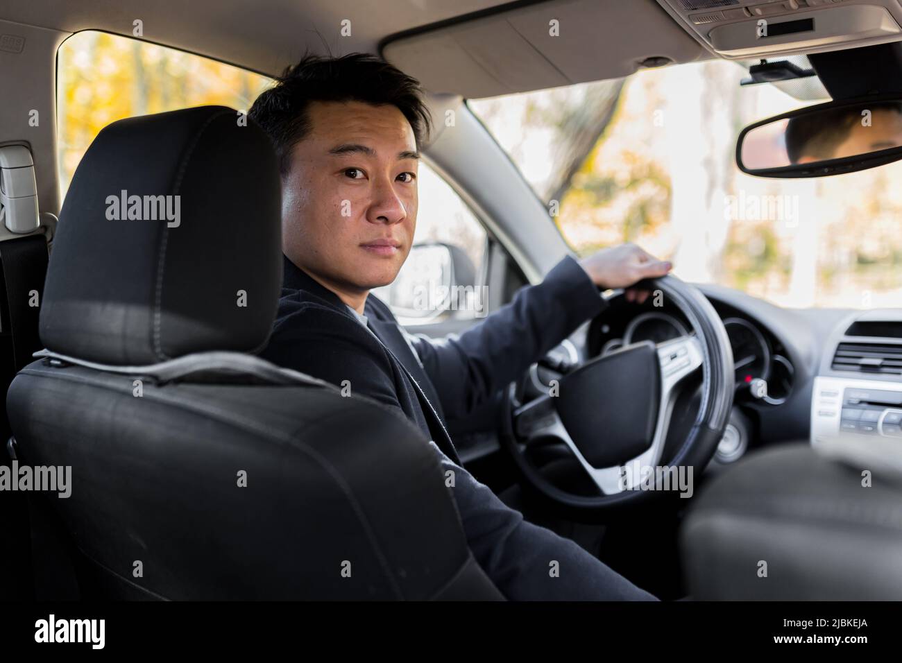 Successful businessman car salesman Male Asian driver behind the wheel ...