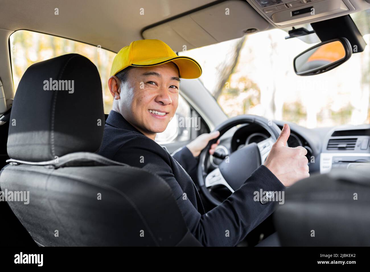 Male courier asian looks into the camera and smiles holding a parcel ...