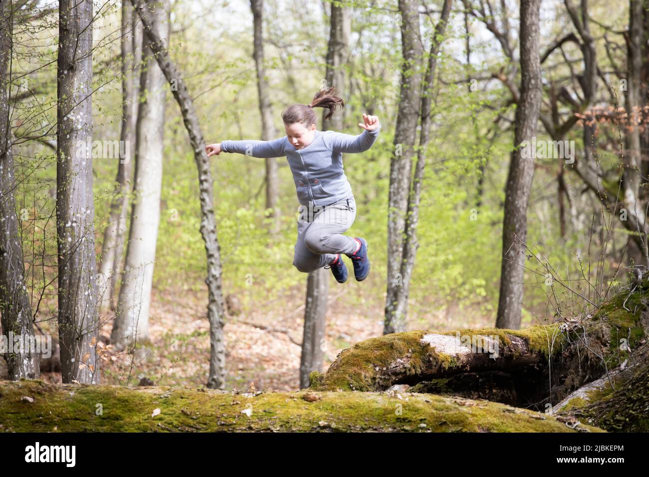 Little girl having fun, jumping in the forest. The concept of outdoor ...