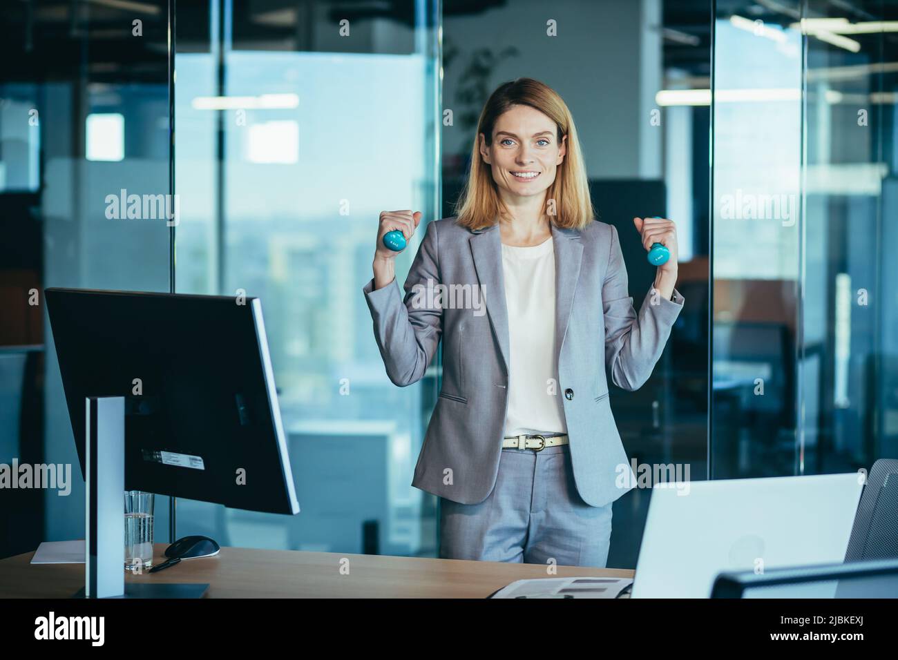Beautiful and happy woman doing sports exercises in the office at work ...