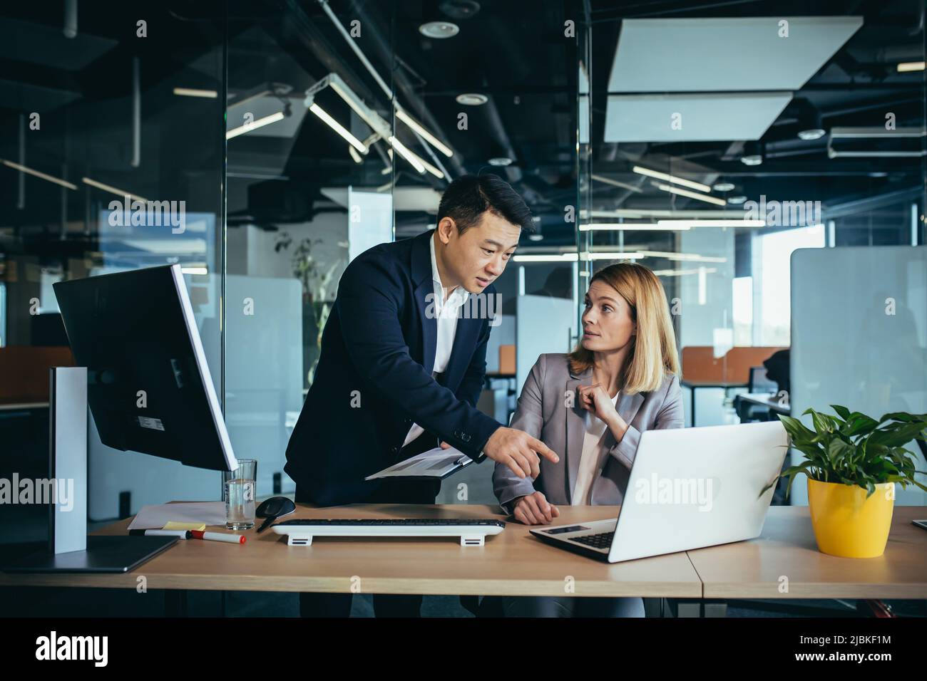 two business people consulting on a project looking at computer monitor ...