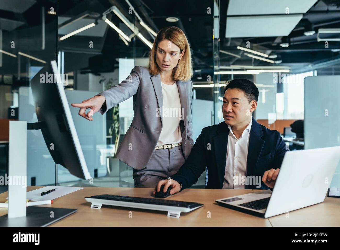 Female boss points to editing colleague on computer monitor, business ...