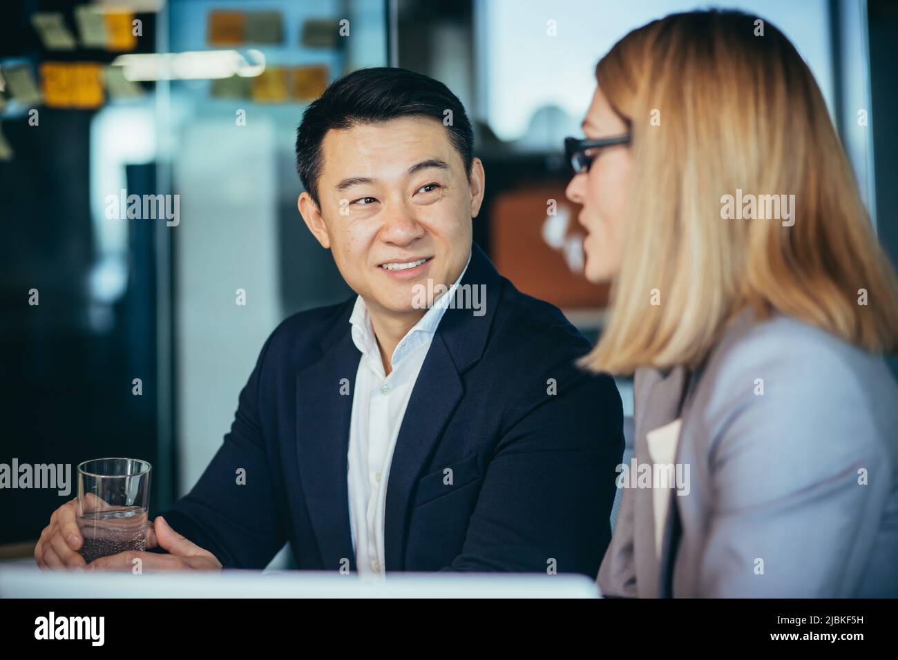 Two employees are having fun. Asian man and blonde woman taking a break ...