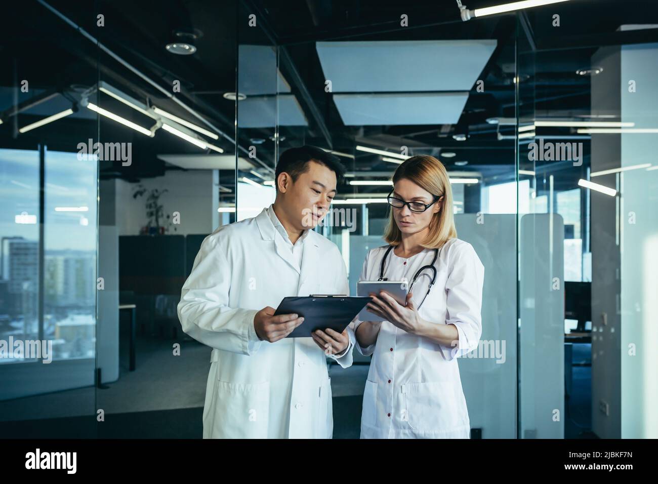 Two doctors, mixed race Asian man and Caucasian woman, communicate ...