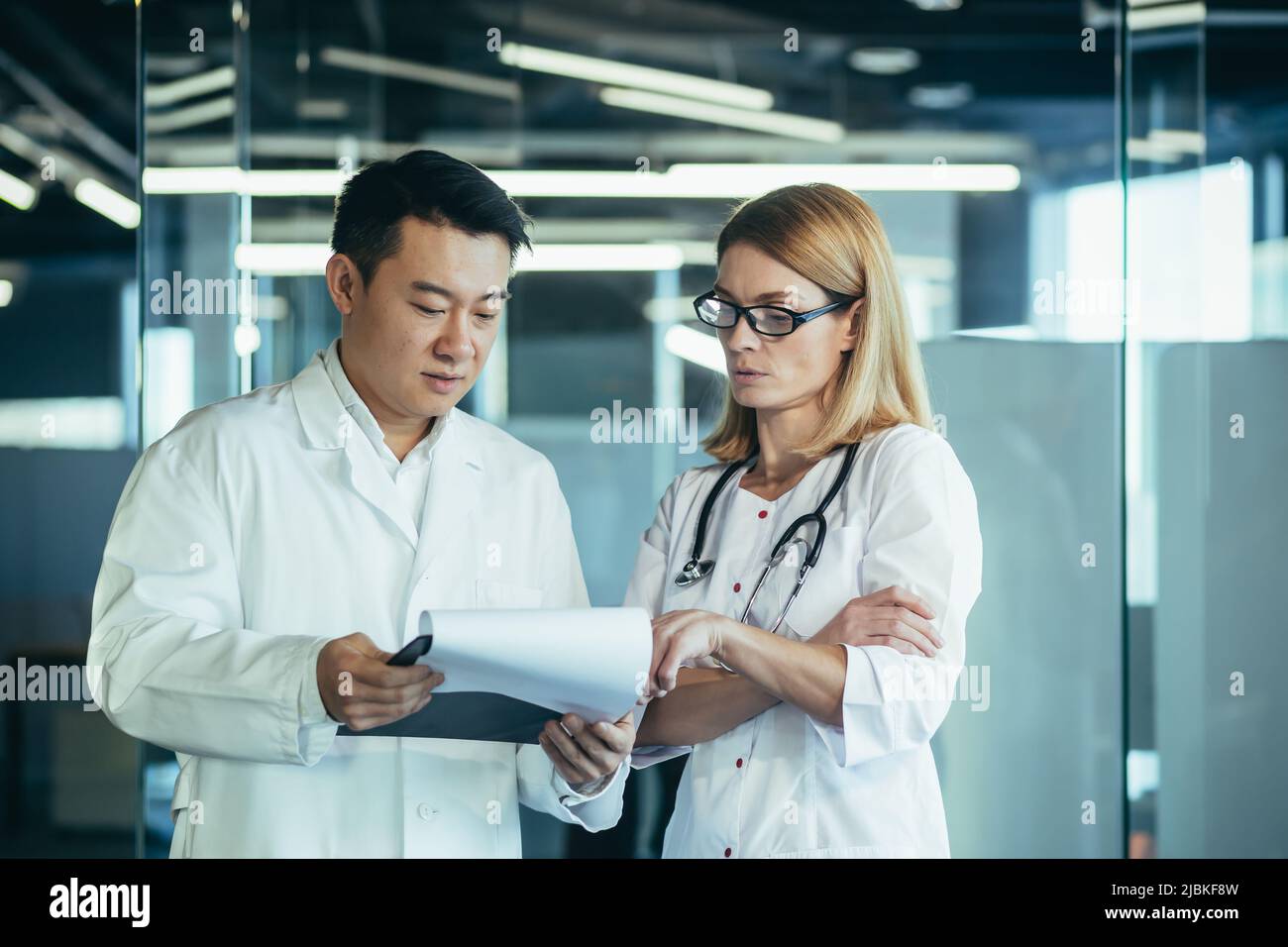 Two doctors, mixed race Asian man and Caucasian woman, communicate ...