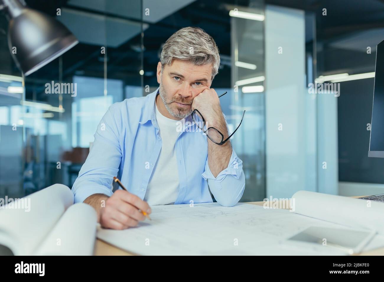 Thinking senior male architect working on an important project. at the ...