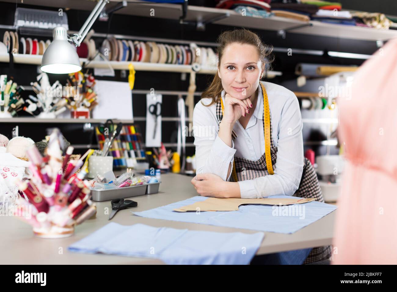 Portrait of female seamstress is who is posing in her design studio ...