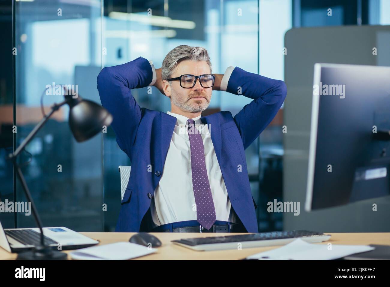 pensive and dreamy experienced businessman owner boss, sitting at work ...