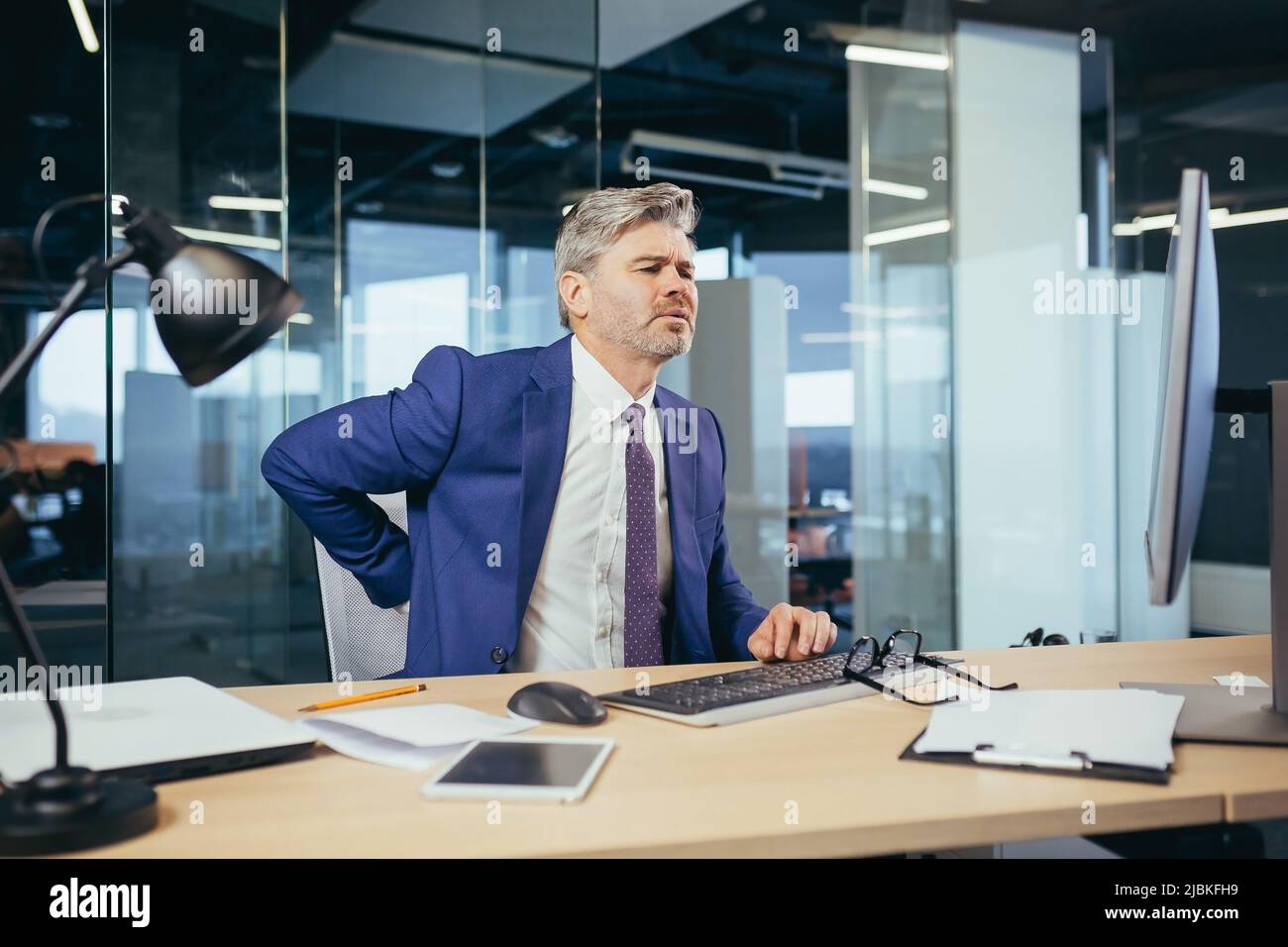 Tired worker businessman working in the office sitting at the computer ...