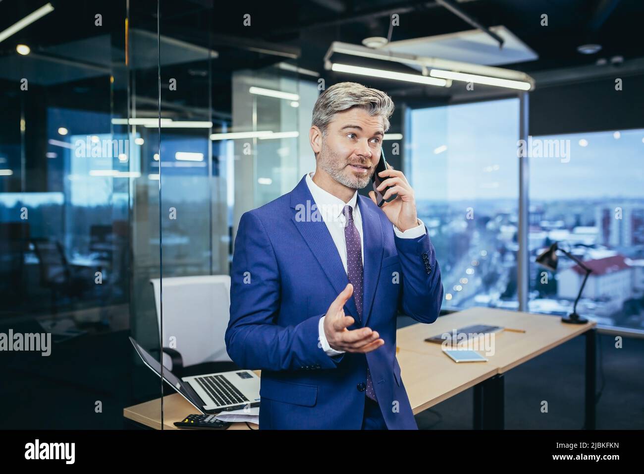 Successful boss working in a modern office, gray-haired businessman ...
