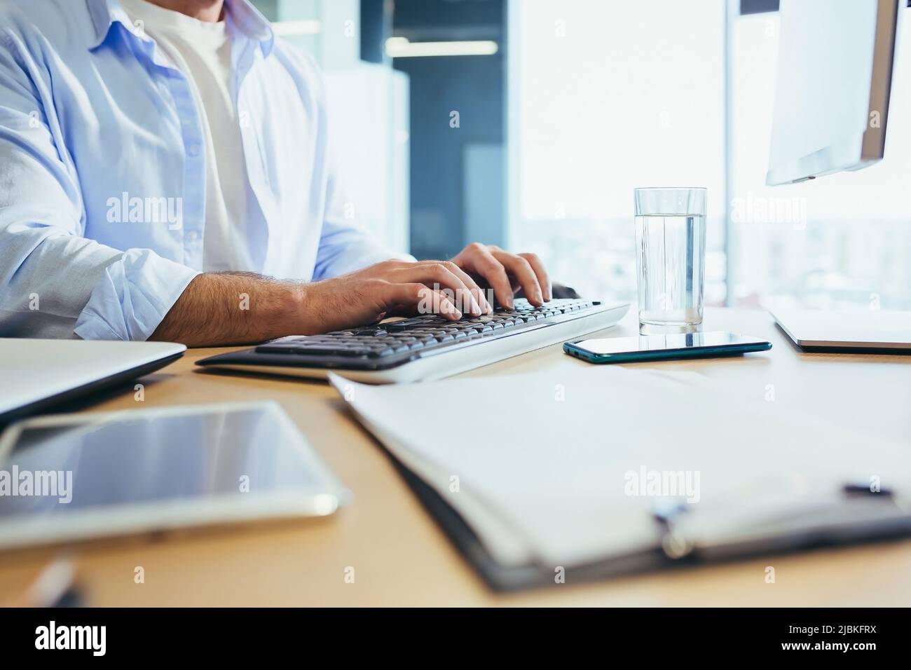 Close-up photo of a man working at a computer, hands on the keyboard ...