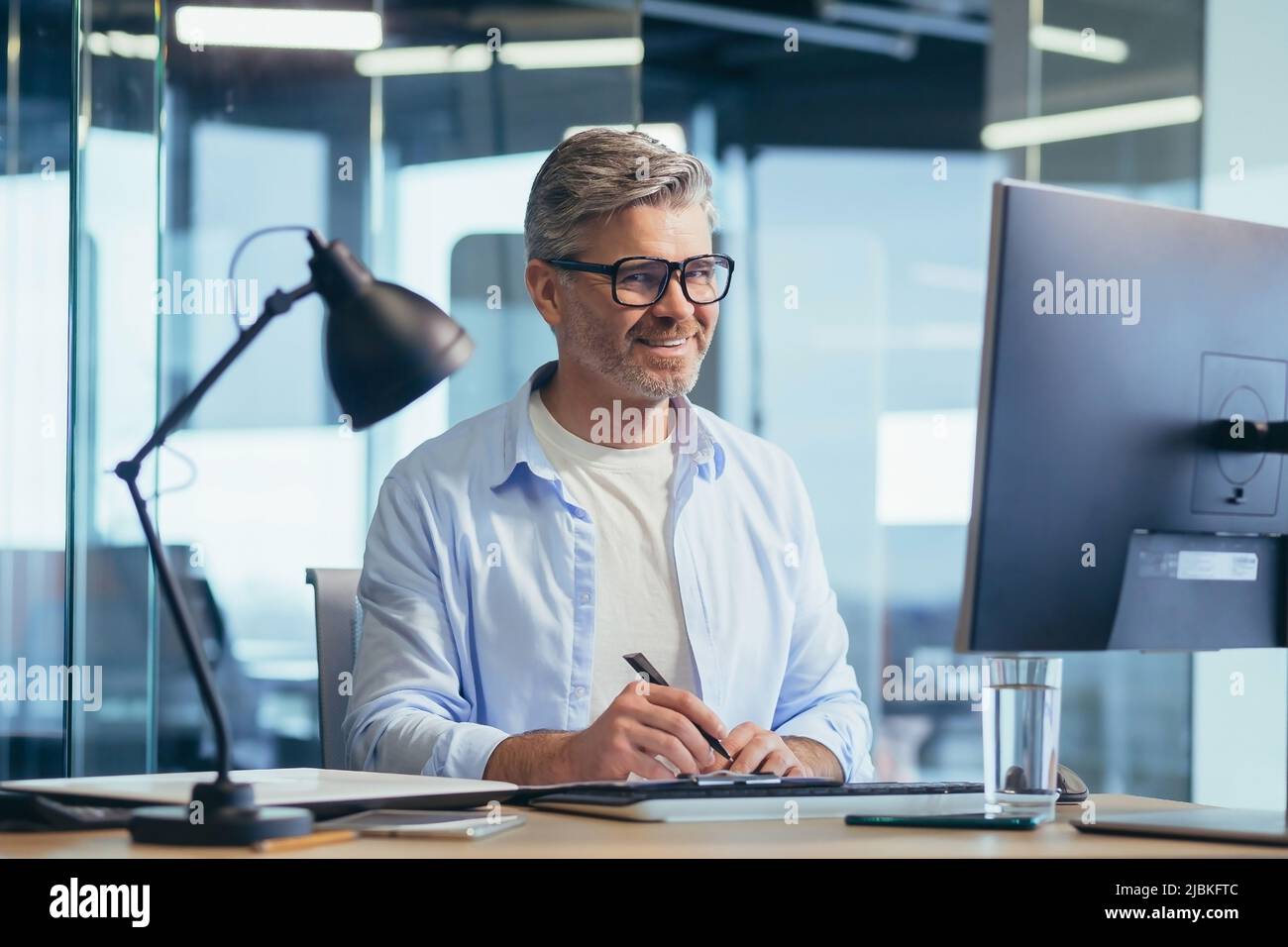 Successful senior boss with glasses, working on computer, businessman ...