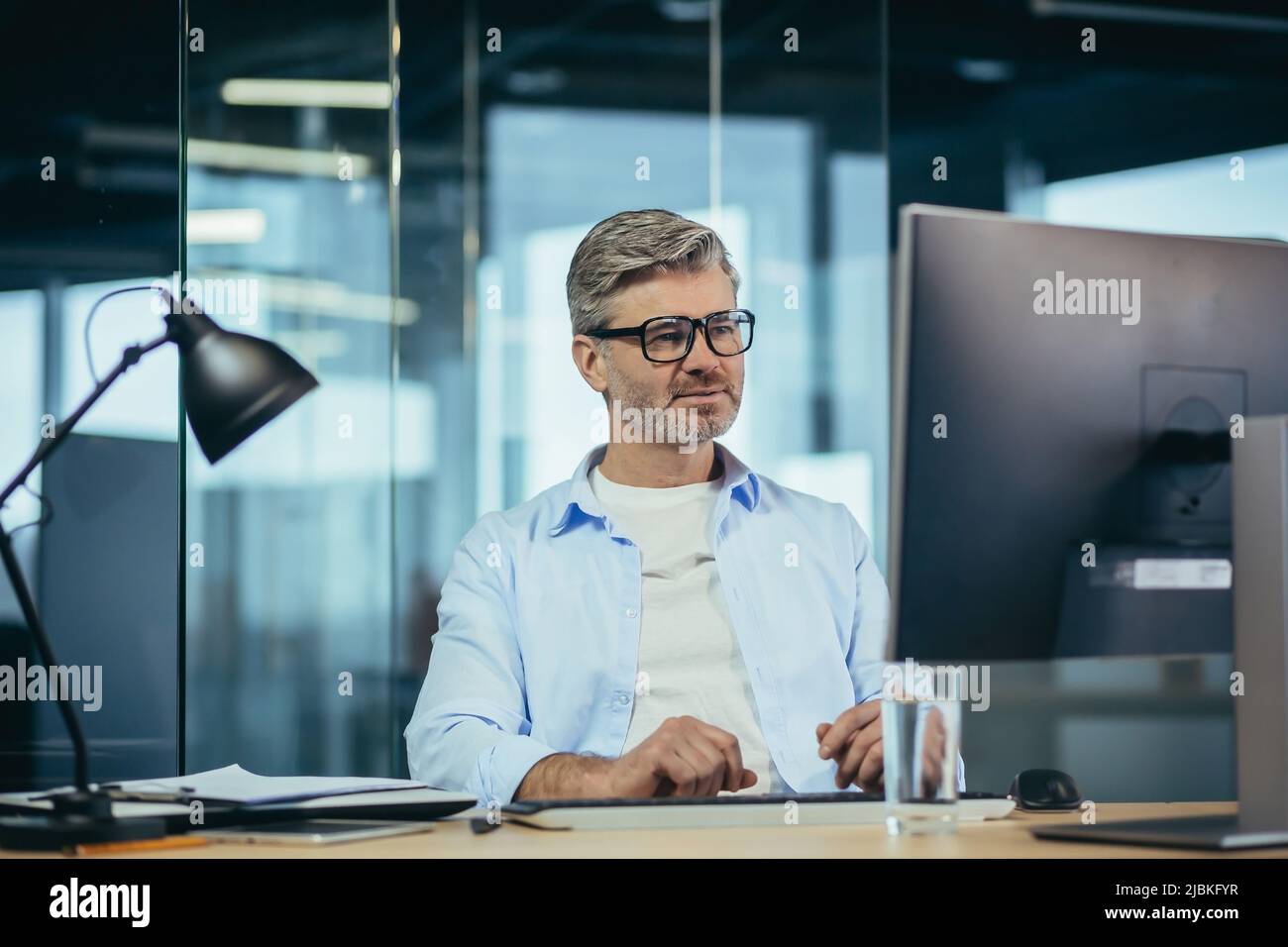 Successful senior boss with glasses, working on computer, businessman ...