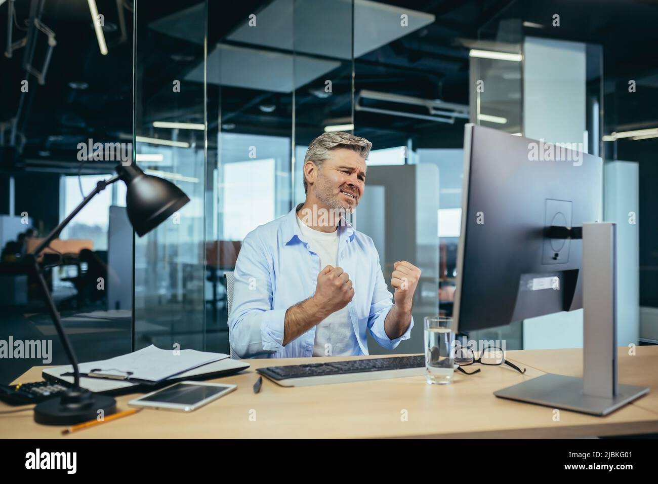 Senior and experienced businessman, looks frustrated at the monitor ...