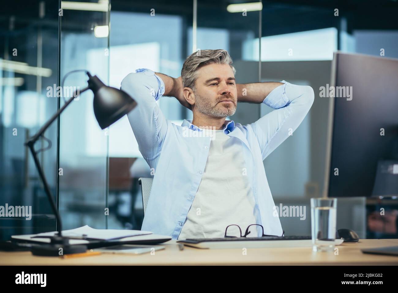 pensive and dreamy experienced businessman owner boss, sitting at work ...
