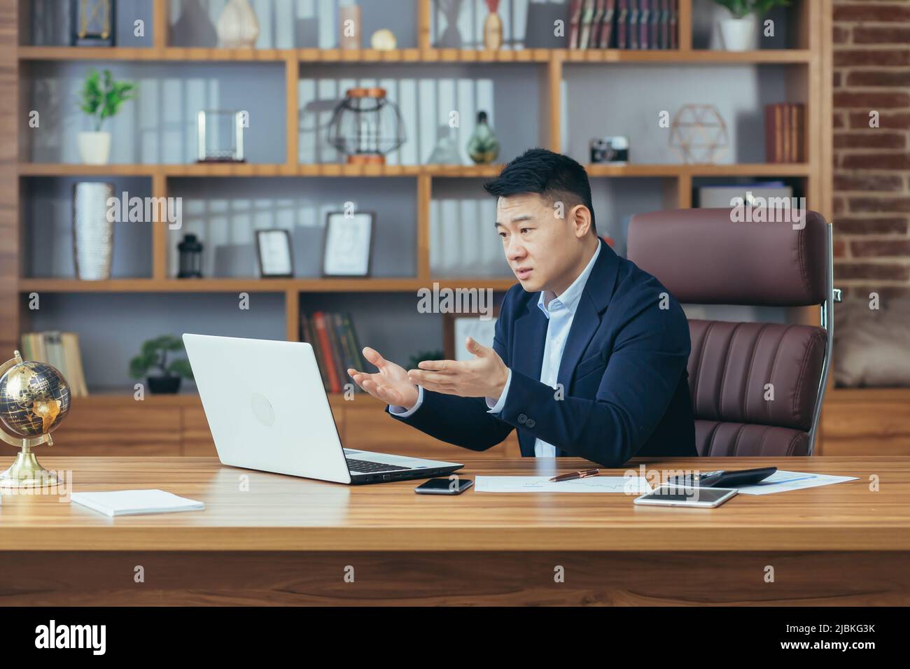 Asian businessman boss talking to colleagues on video call, looking at ...